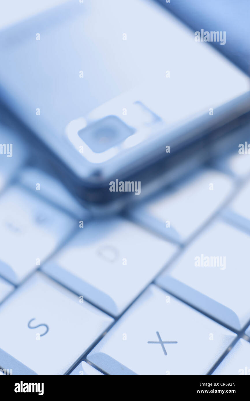 Cell phone on keyboard in office, close up Stock Photo - Alamy