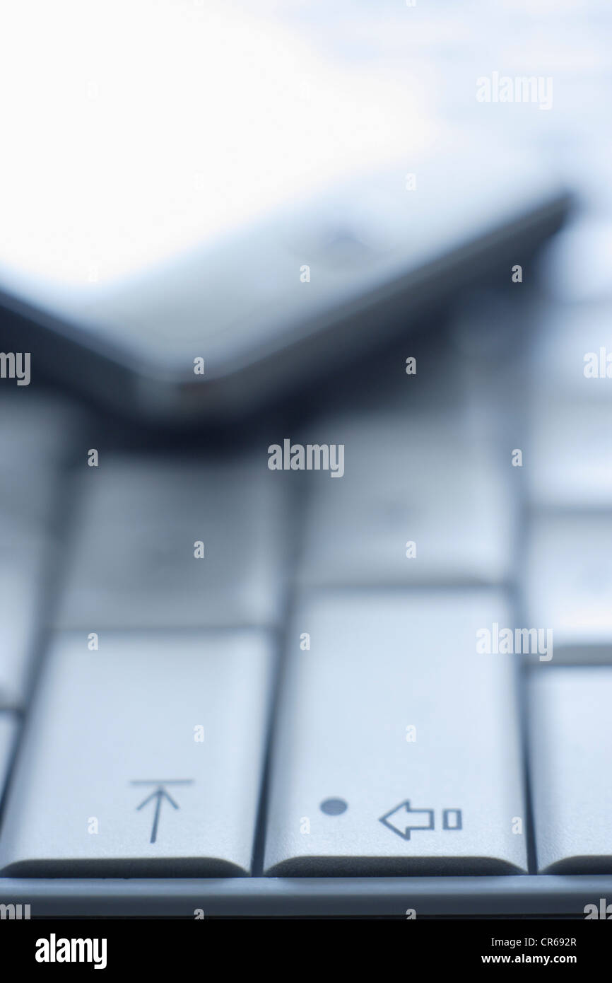 Cell phone on keyboard in office, close up Stock Photo - Alamy