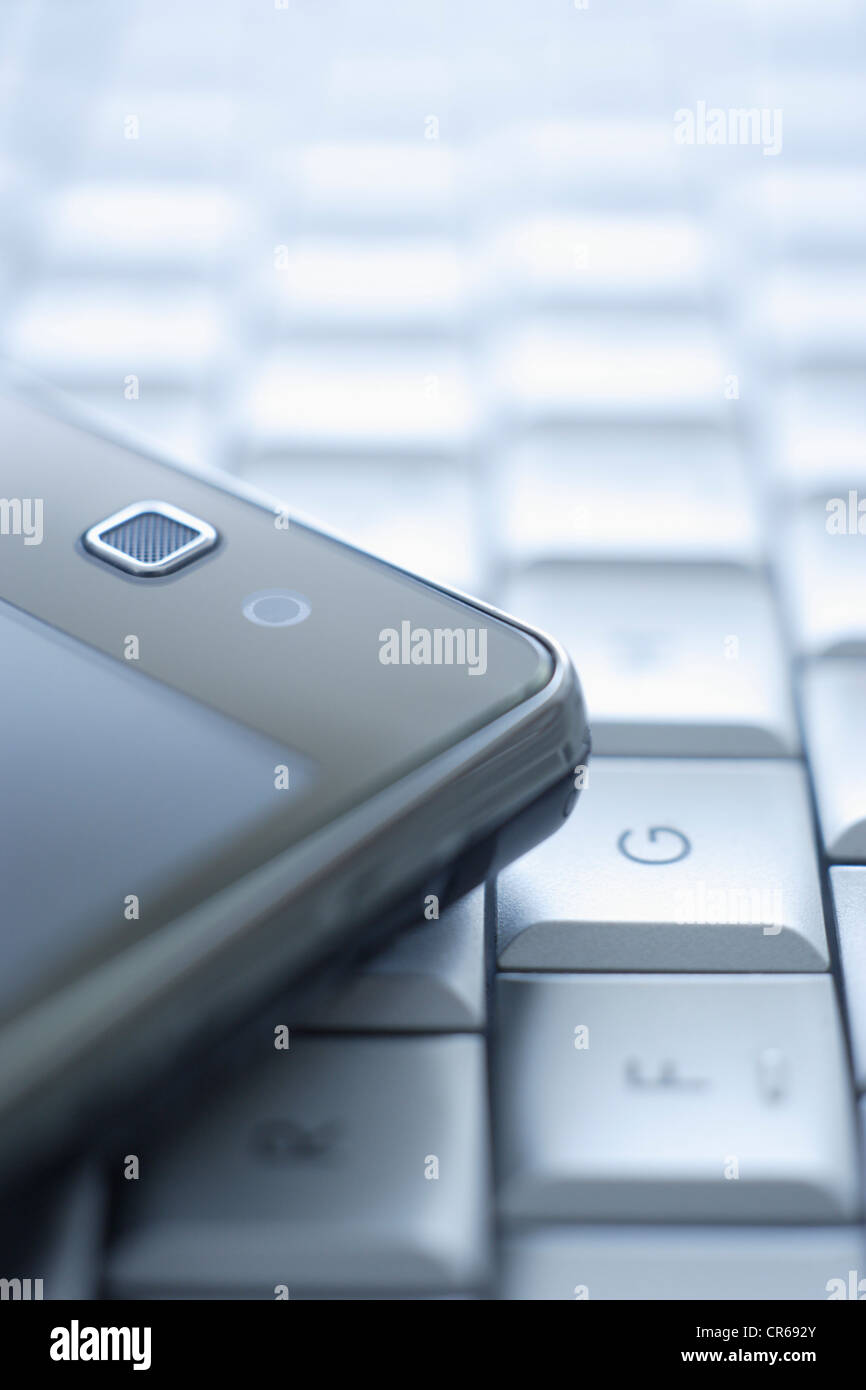 Cell phone on keyboard in office, close up Stock Photo - Alamy
