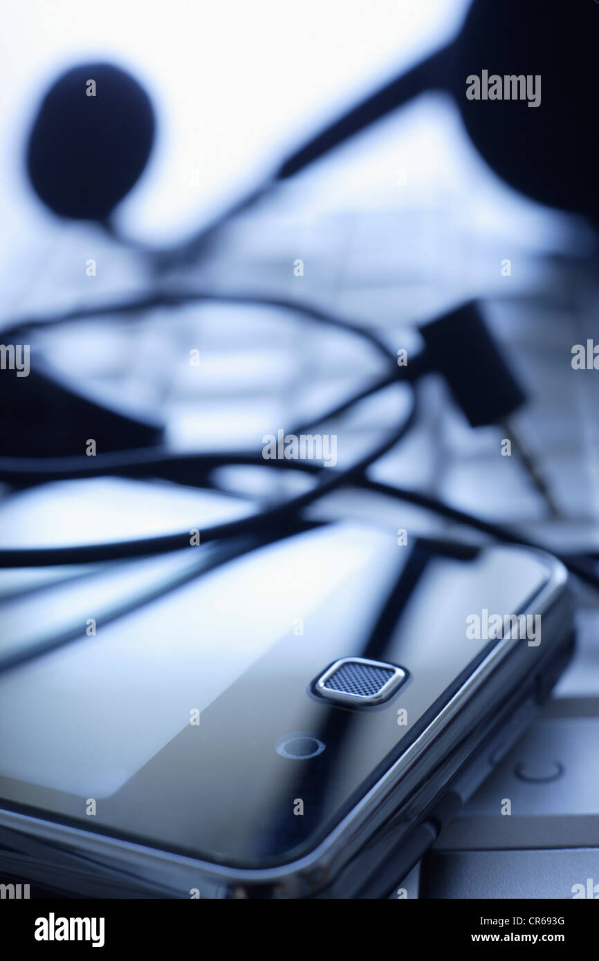 Cell phone on keyboard with headset in office, close up Stock Photo - Alamy