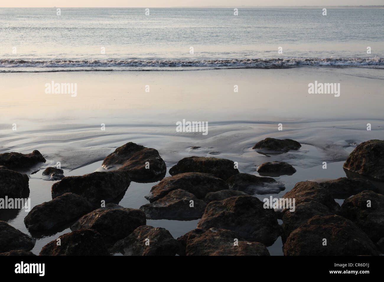 It' a photo of rocks on the beach near the ocean or the sea. It' the ...