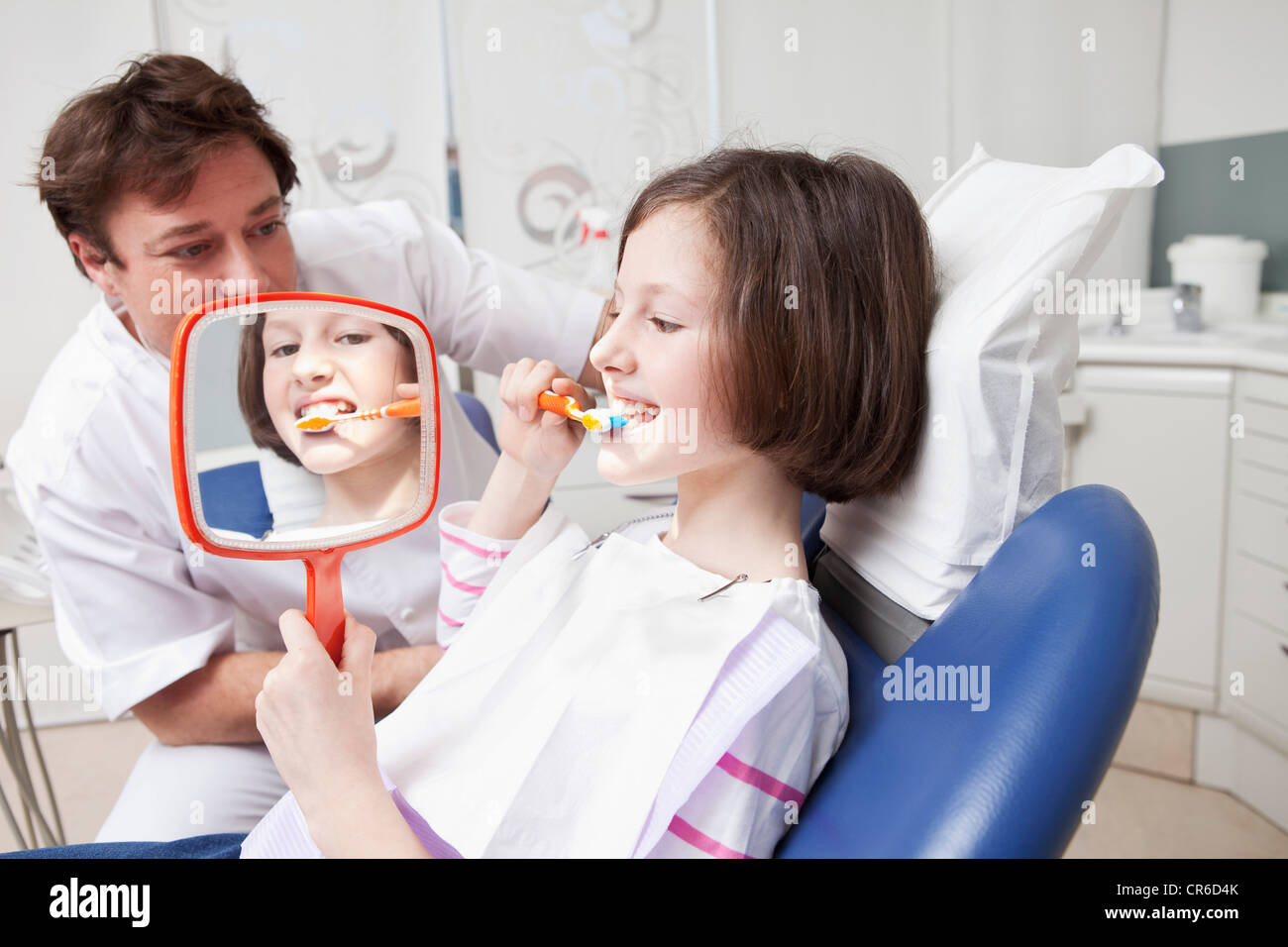Germany, Bavaria, Patient brushing teeth while doctor looking at her ...