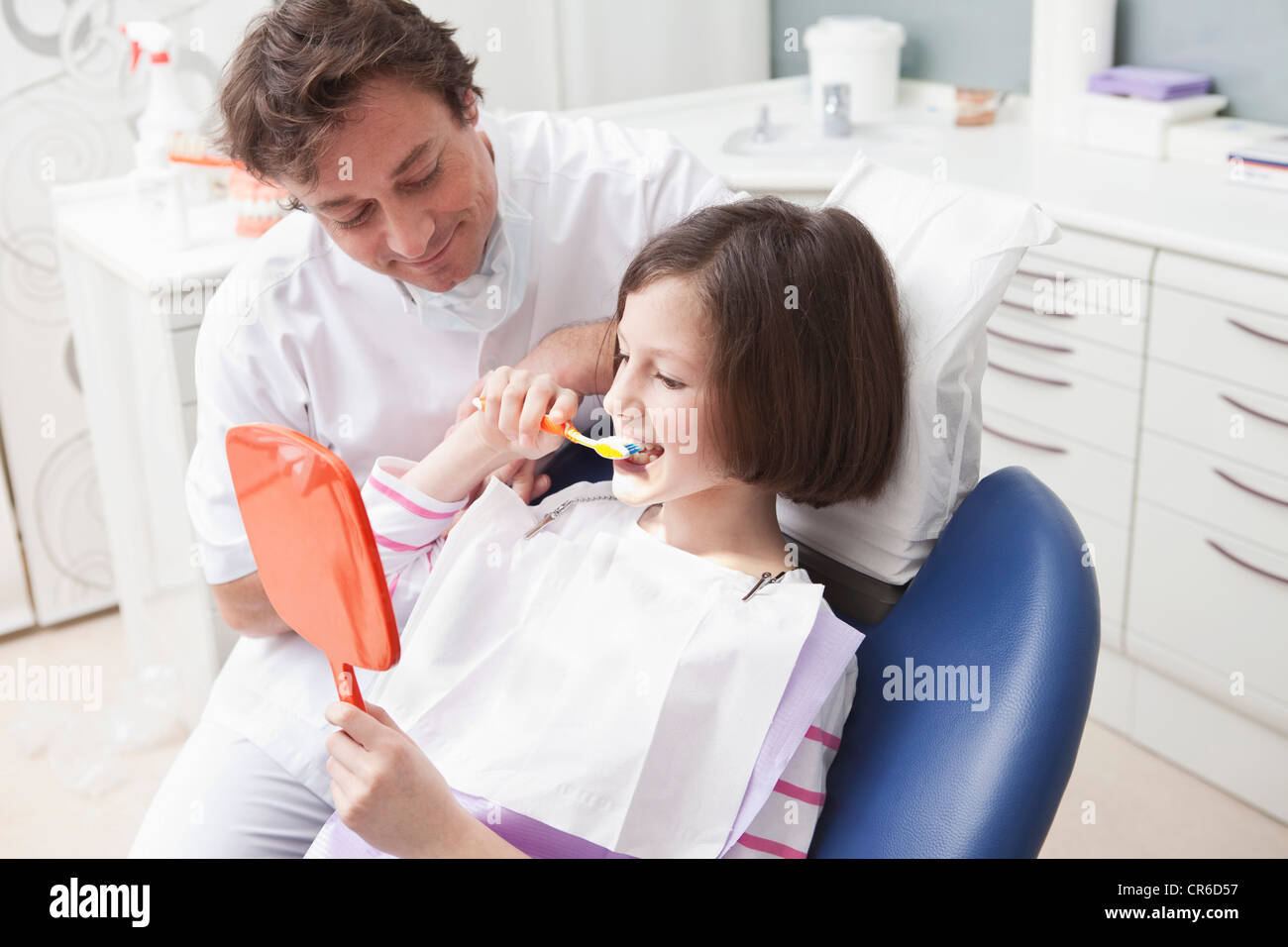 Germany, Bavaria, Patient brushing teeth while doctor looking at her ...