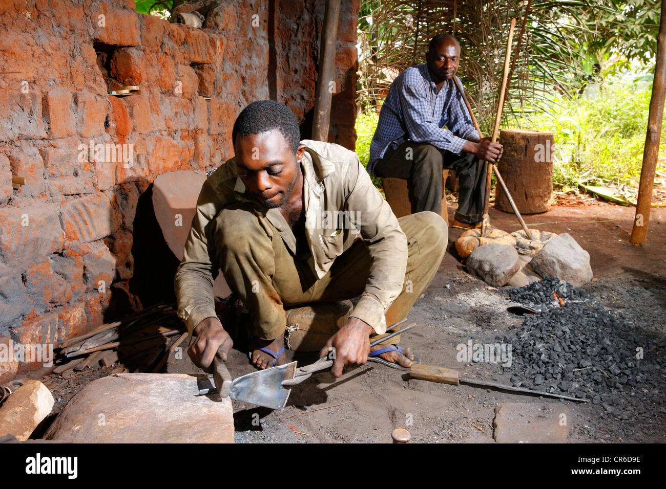 Smith making a musical instrument from scrap metal, and another man ...