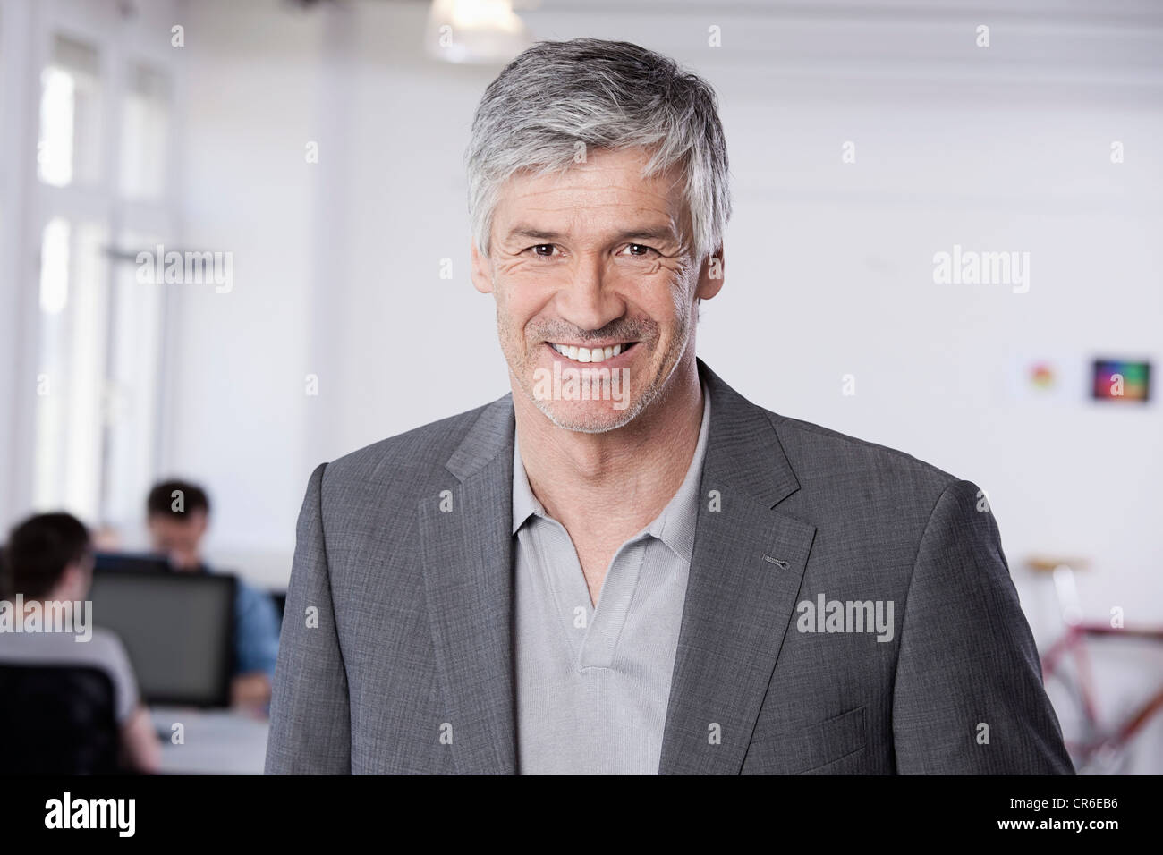 Germany, Bavaria, Munich, Mature man standing in office, colleagues ...