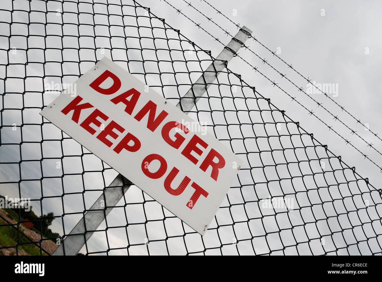Danger Keep Out sign on a chain link fence topped with barbed wire ...