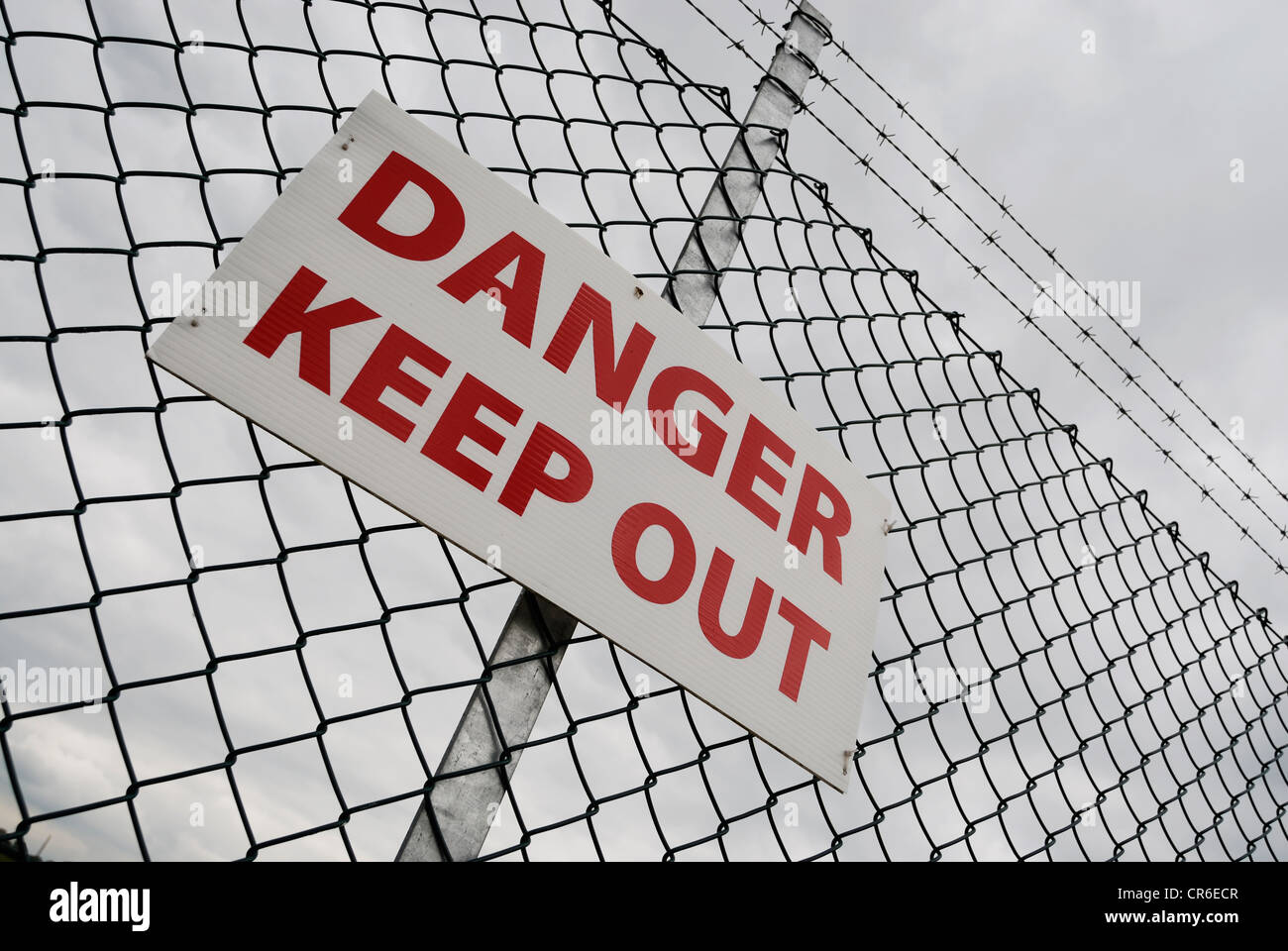 Danger Keep Out sign on a chain link fence topped with barbed wire ...