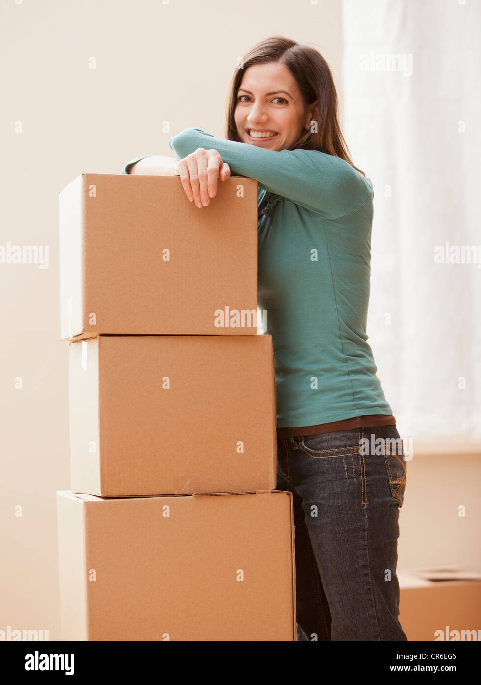 Mid adult woman leaning on cardboard boxes Stock Photo - Alamy