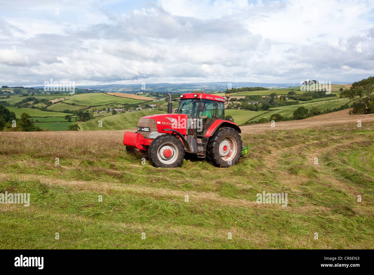 Farmer in a tractor making hay, South Hams hills, Totnes, Devon ...