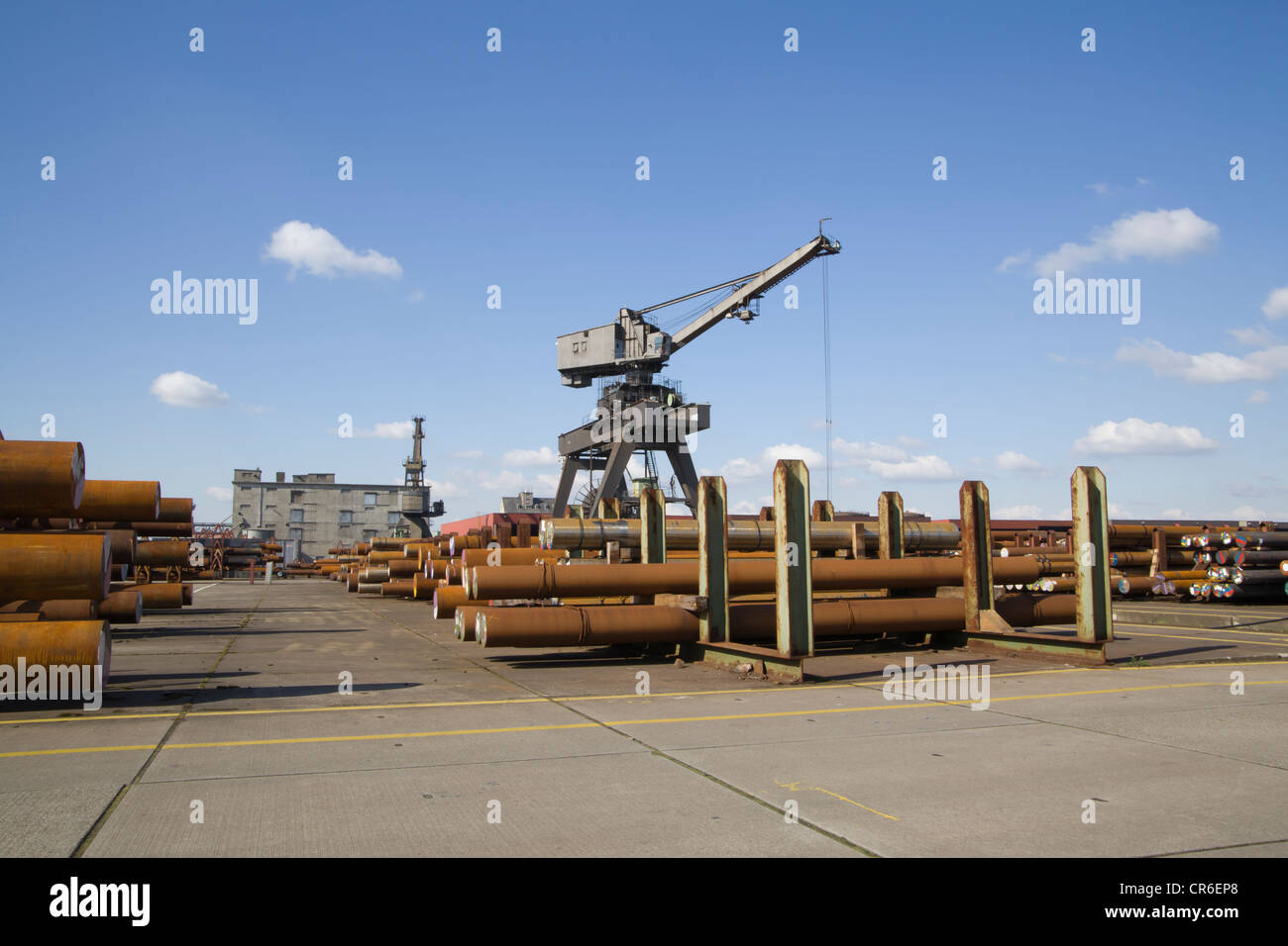 Germany, North Rhine Westphalia, Neuss, Crane lifting pipe at steel ...