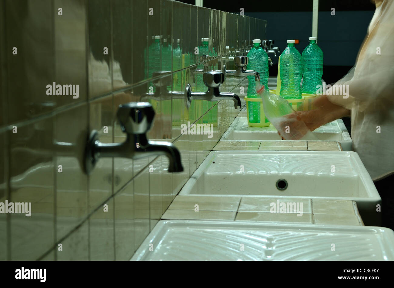 Man getting water in plastic bottles, public toilet, camping ground ...