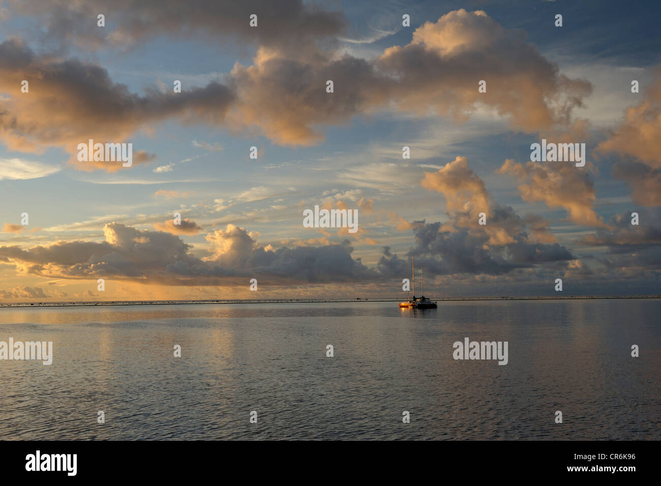 Sunrise over North Minerva Reef, with a cruising trimaran, anchored in ...