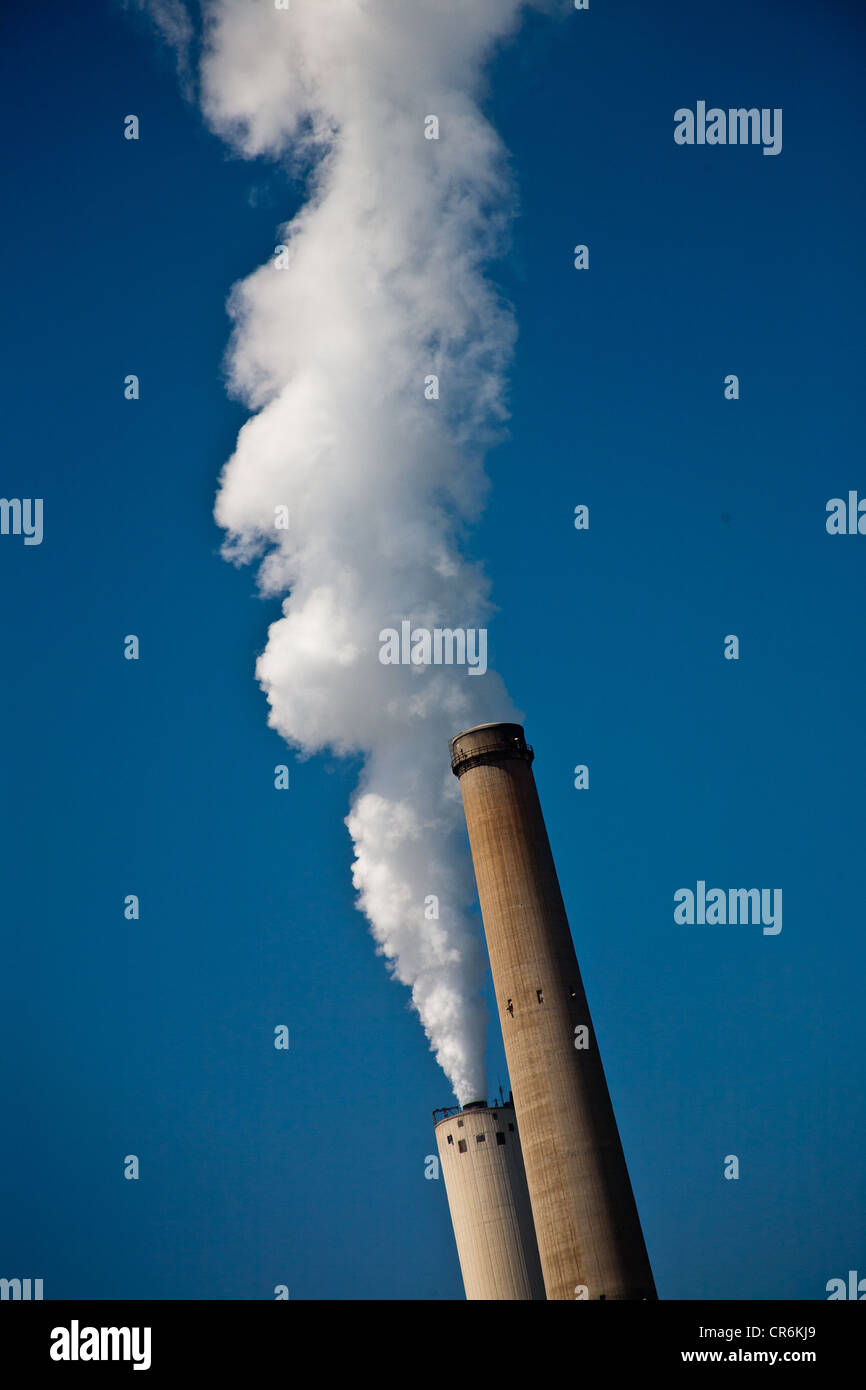 Two chimneys blow smoke into blue sky Stock Photo - Alamy