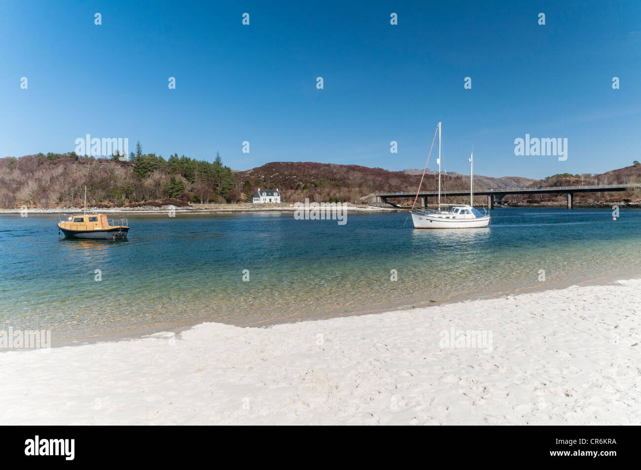 Yacht at white sands of Morar with cottage and road bridge nr Mallaig ...