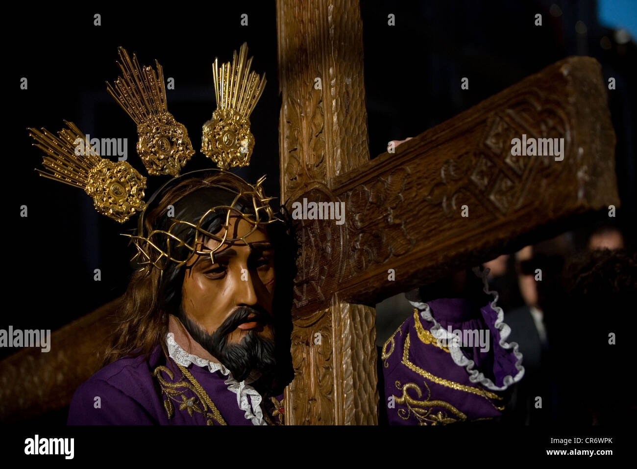 A masked man dressed as Jesus Christ carries a cross during an Easter ...