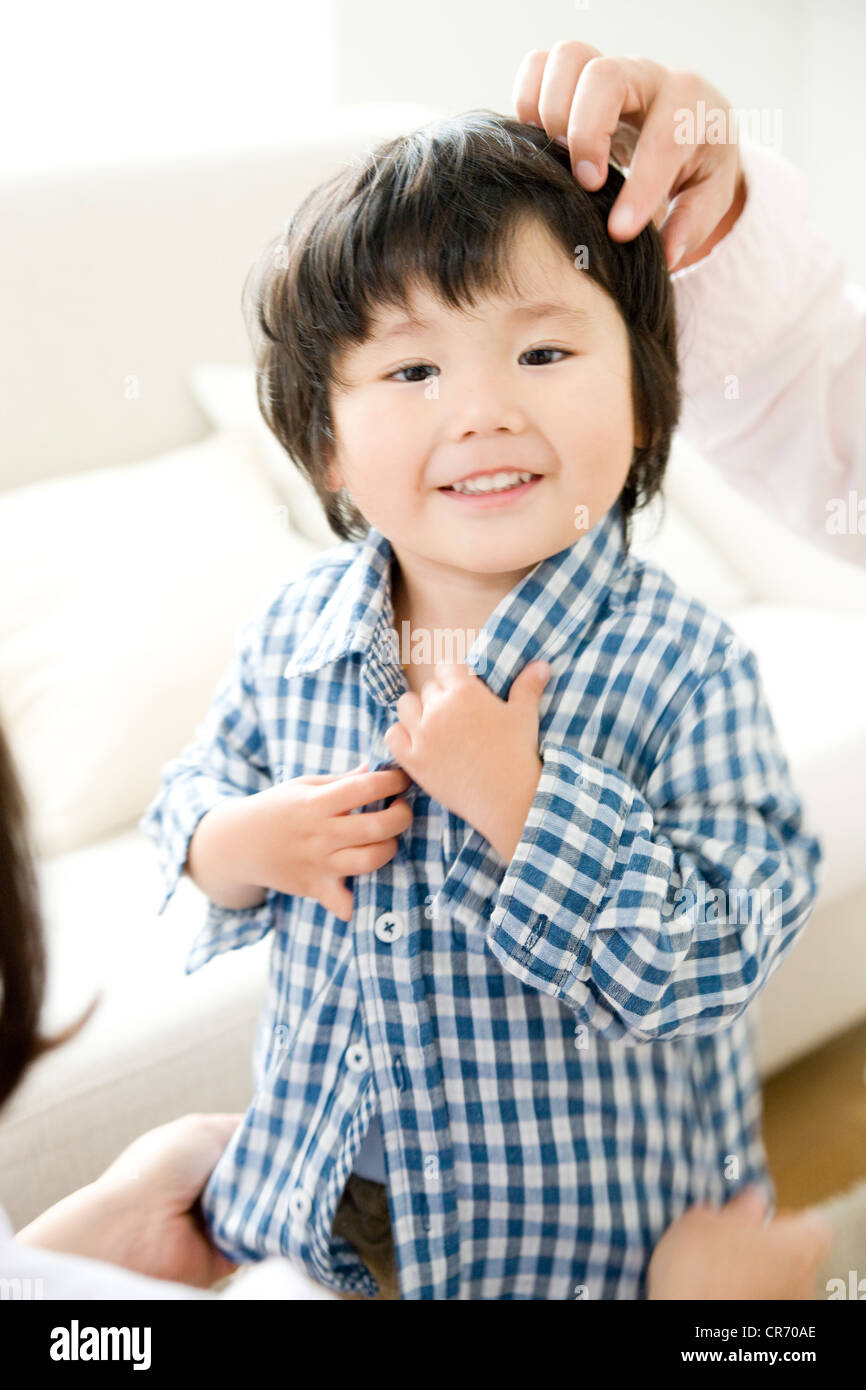 Boy putting on shirt Stock Photo - Alamy