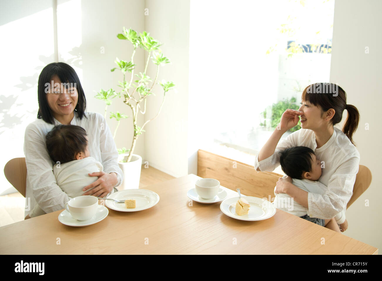 Mothers and babies sitting at table Stock Photo - Alamy