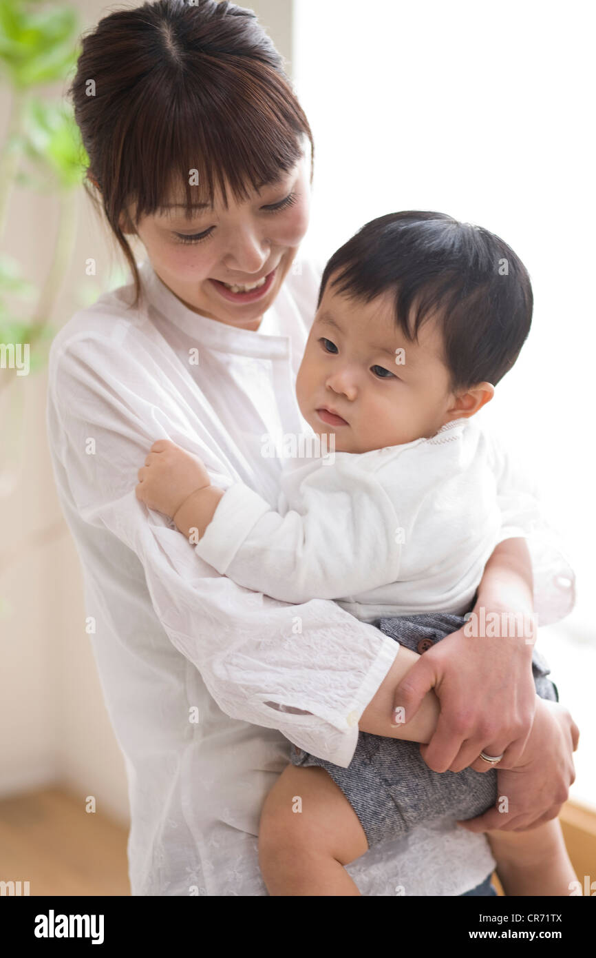 Mother and baby hugging in living room Stock Photo - Alamy