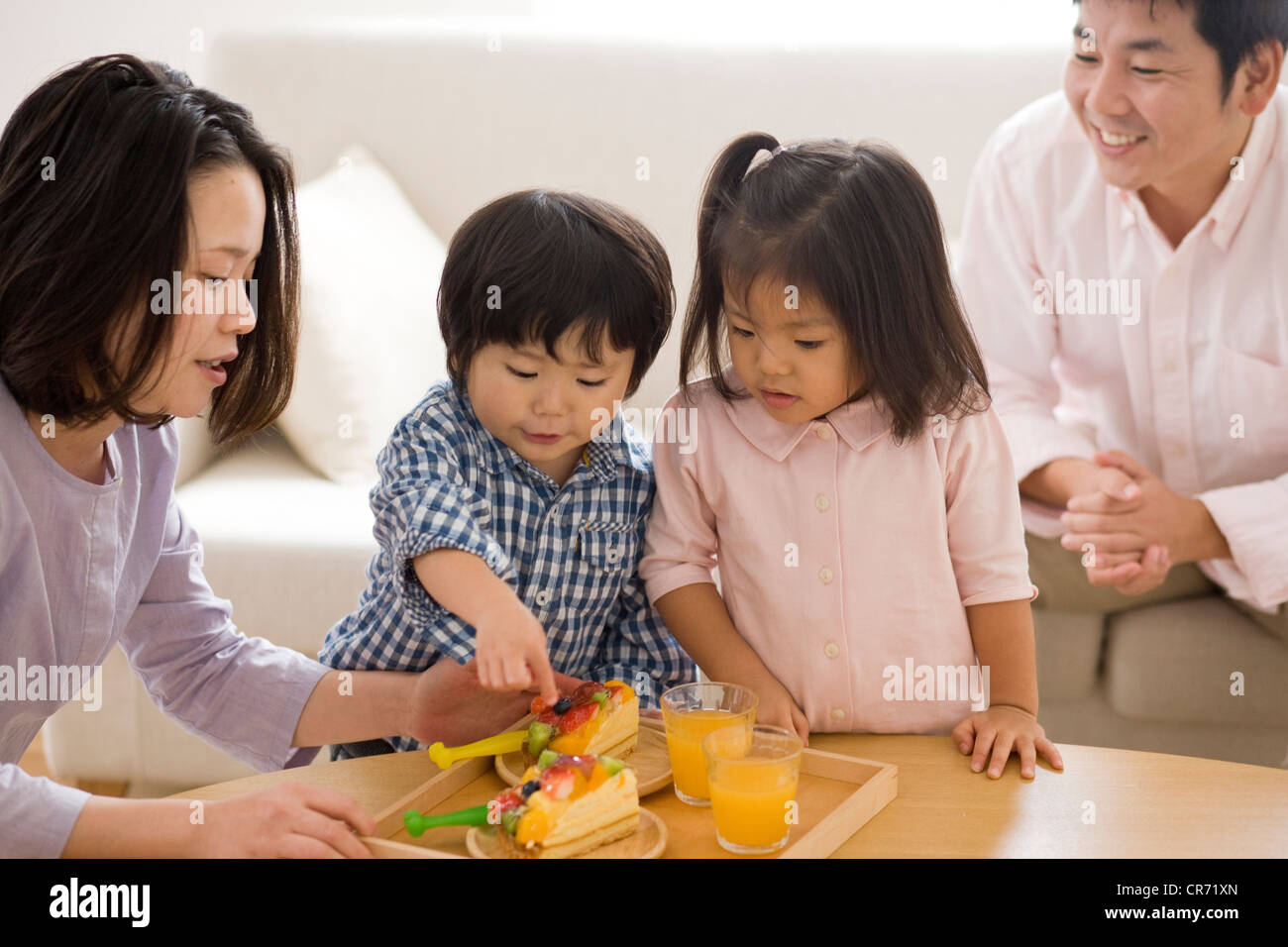 Family eating cake in living room Stock Photo - Alamy