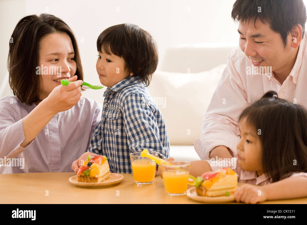 Family eating cake in living room Stock Photo - Alamy
