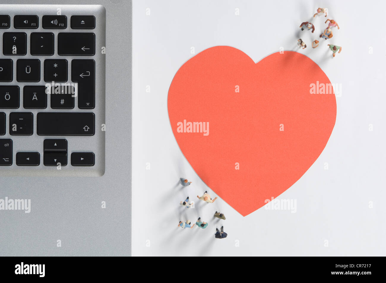 Figurines and heart shape with laptop on white background Stock Photo ...