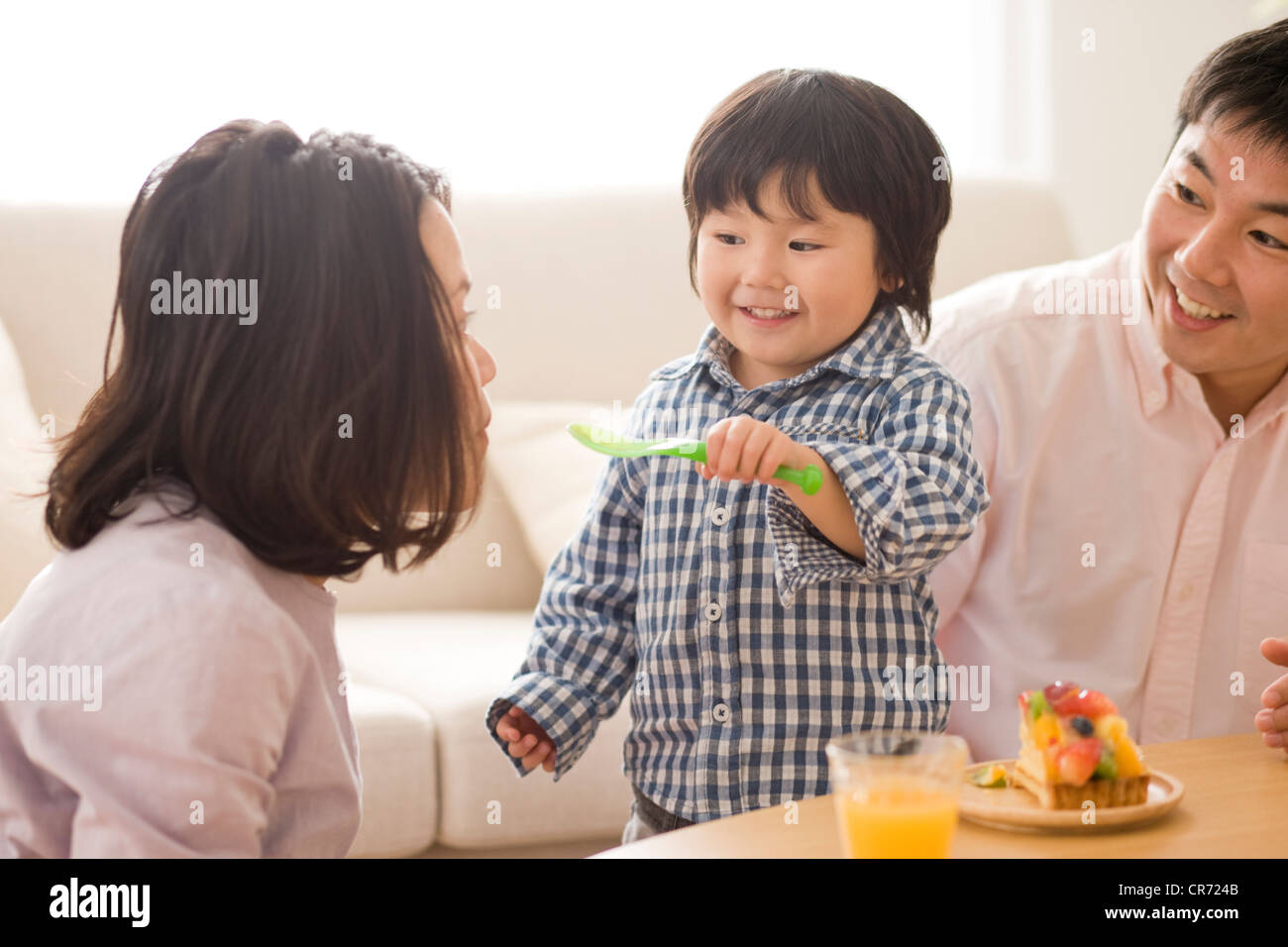 Family eating cake in living room Stock Photo - Alamy
