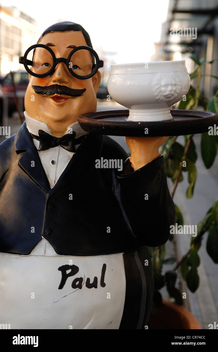 Butler figure carrying a soup bowl on a tray in front of a café ...