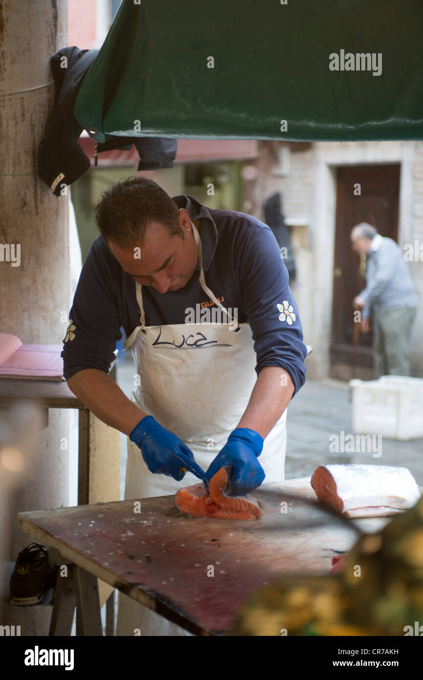 A fish monger filleting Salmon at a fish market, Venice Italy Stock ...