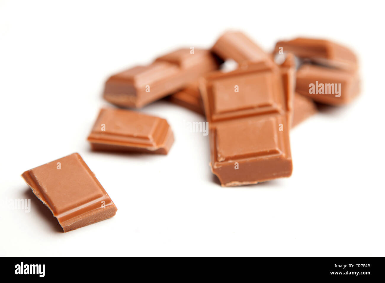 Squares of milk chocolate scattered across a white background Stock ...