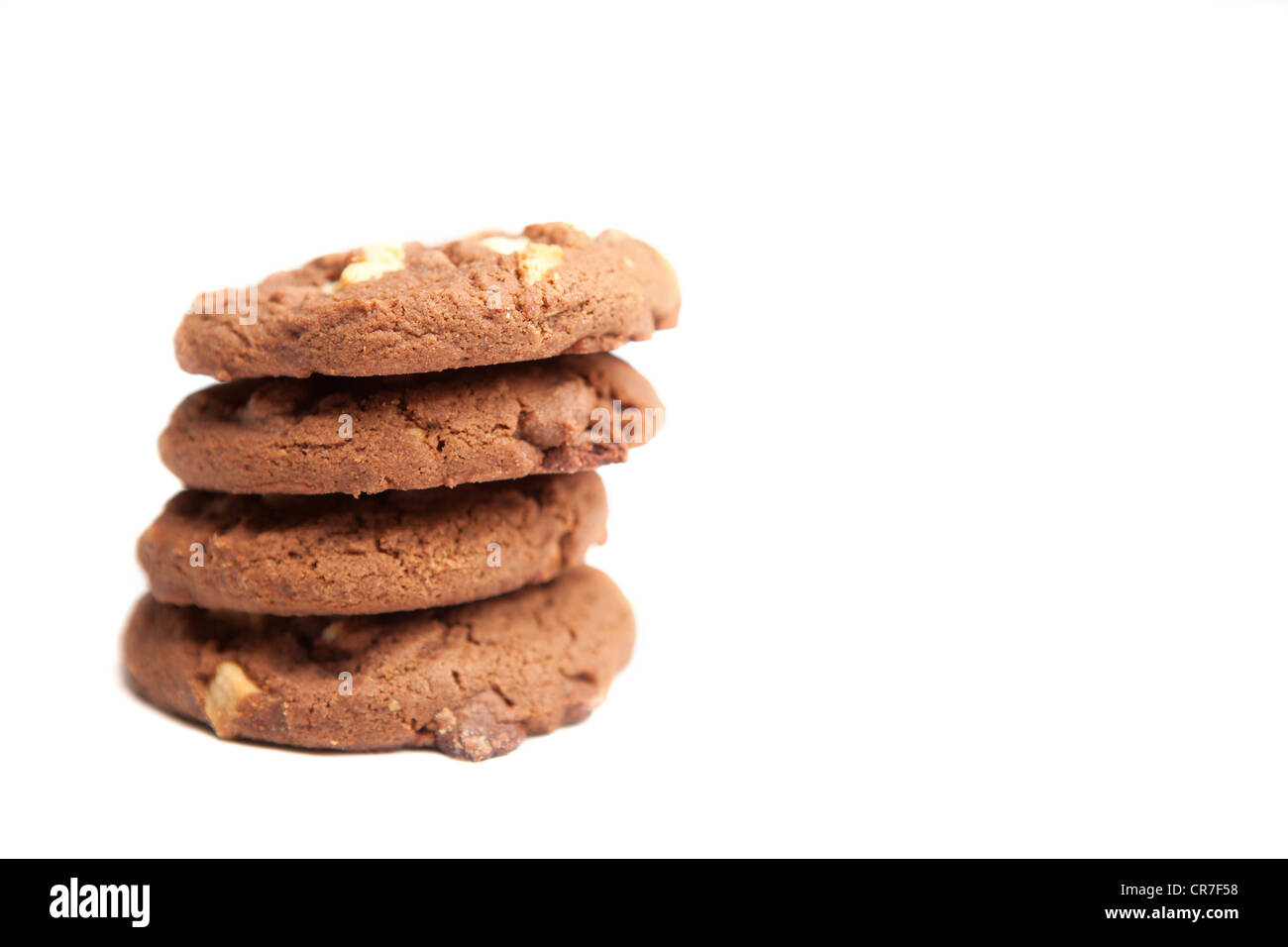 Four chocolate chip cookies stacked up in a tower, set on a white ...