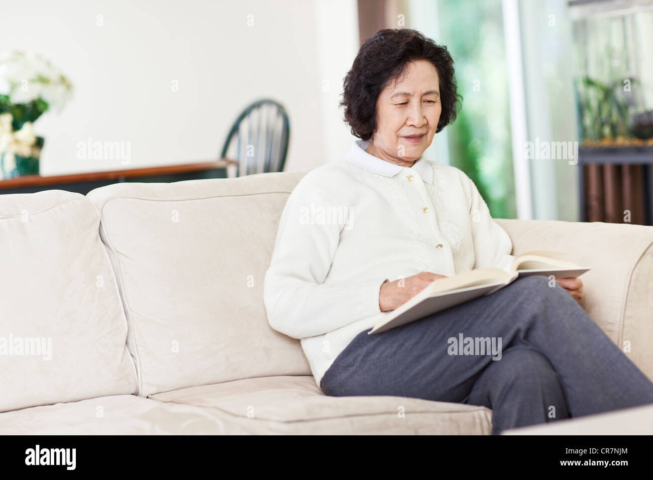 Chinese woman on sofa reading book Stock Photo - Alamy