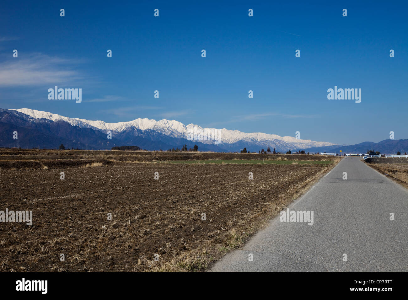 Snowcapped mountain chain behind rural landscape Stock Photo - Alamy