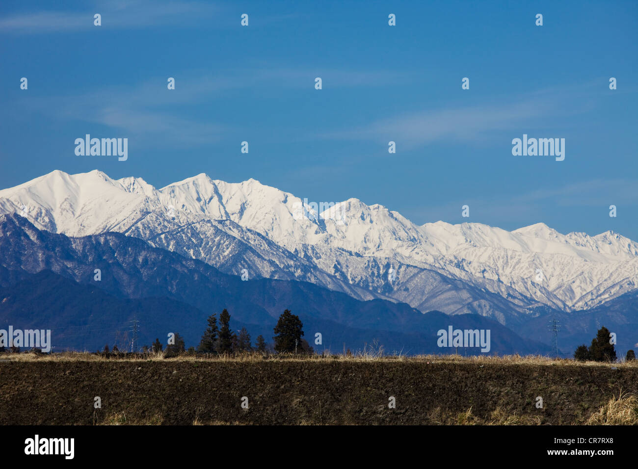 Snowcapped mountain chain behind rural landscape Stock Photo - Alamy