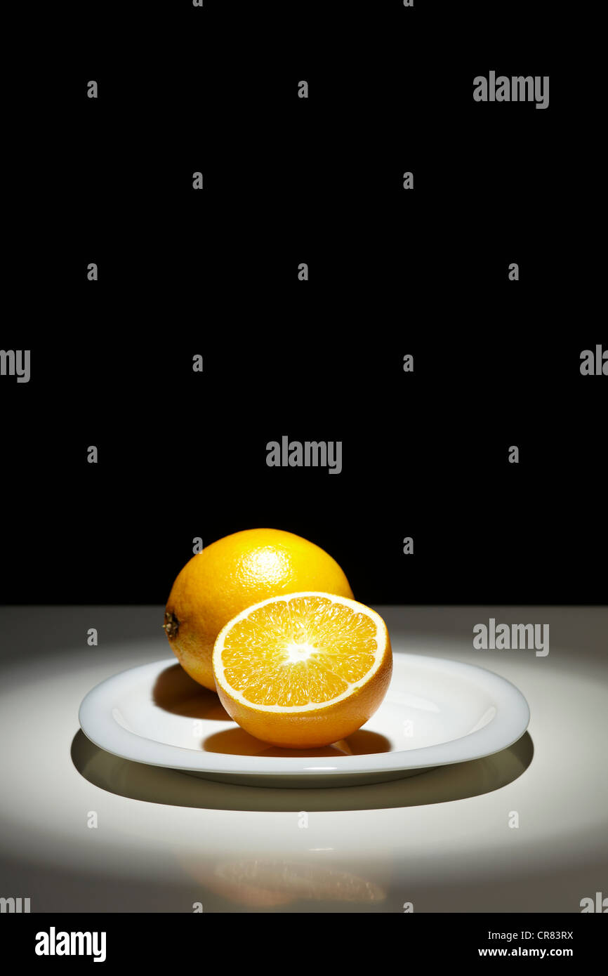 Two oranges (Citrus sinensis), one whole orange and one halved orange ...