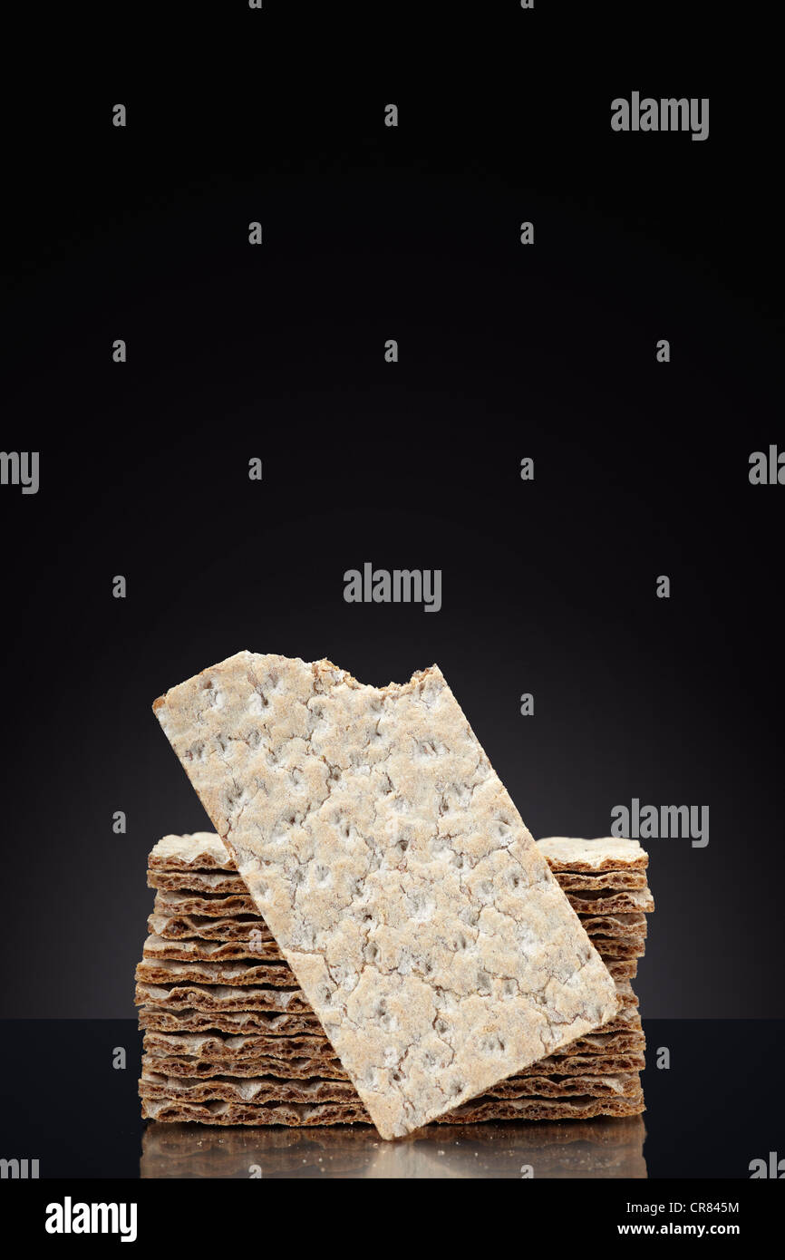 Slice of crispbread bitten into, on a dark glass plate Stock Photo - Alamy