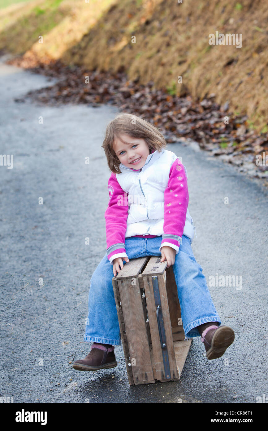 Girl, 4, sitting on a wooden crate Stock Photo - Alamy