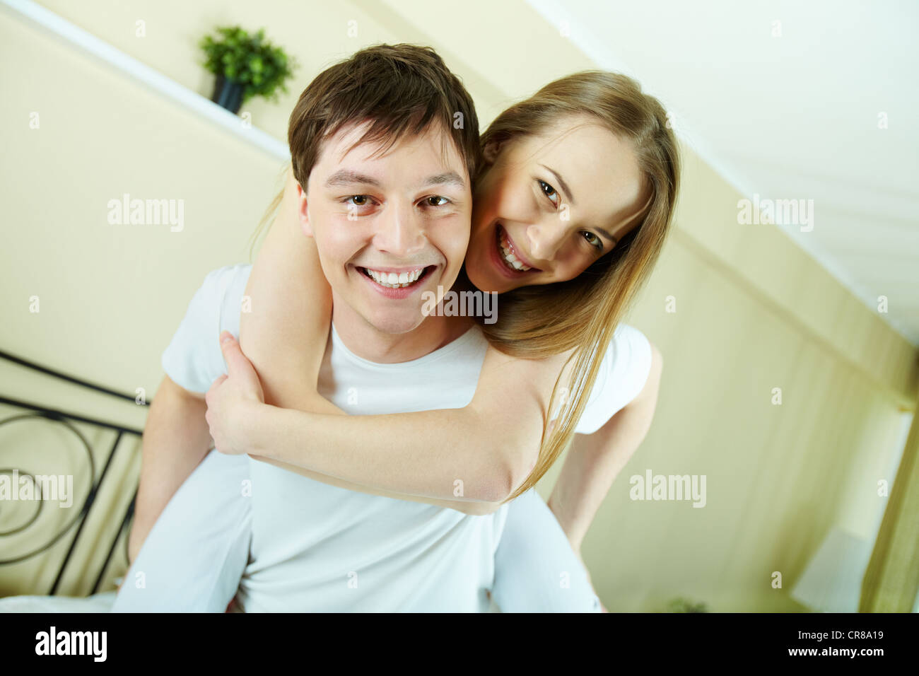 Happy girl embracing her boyfriend on his back and both looking at ...