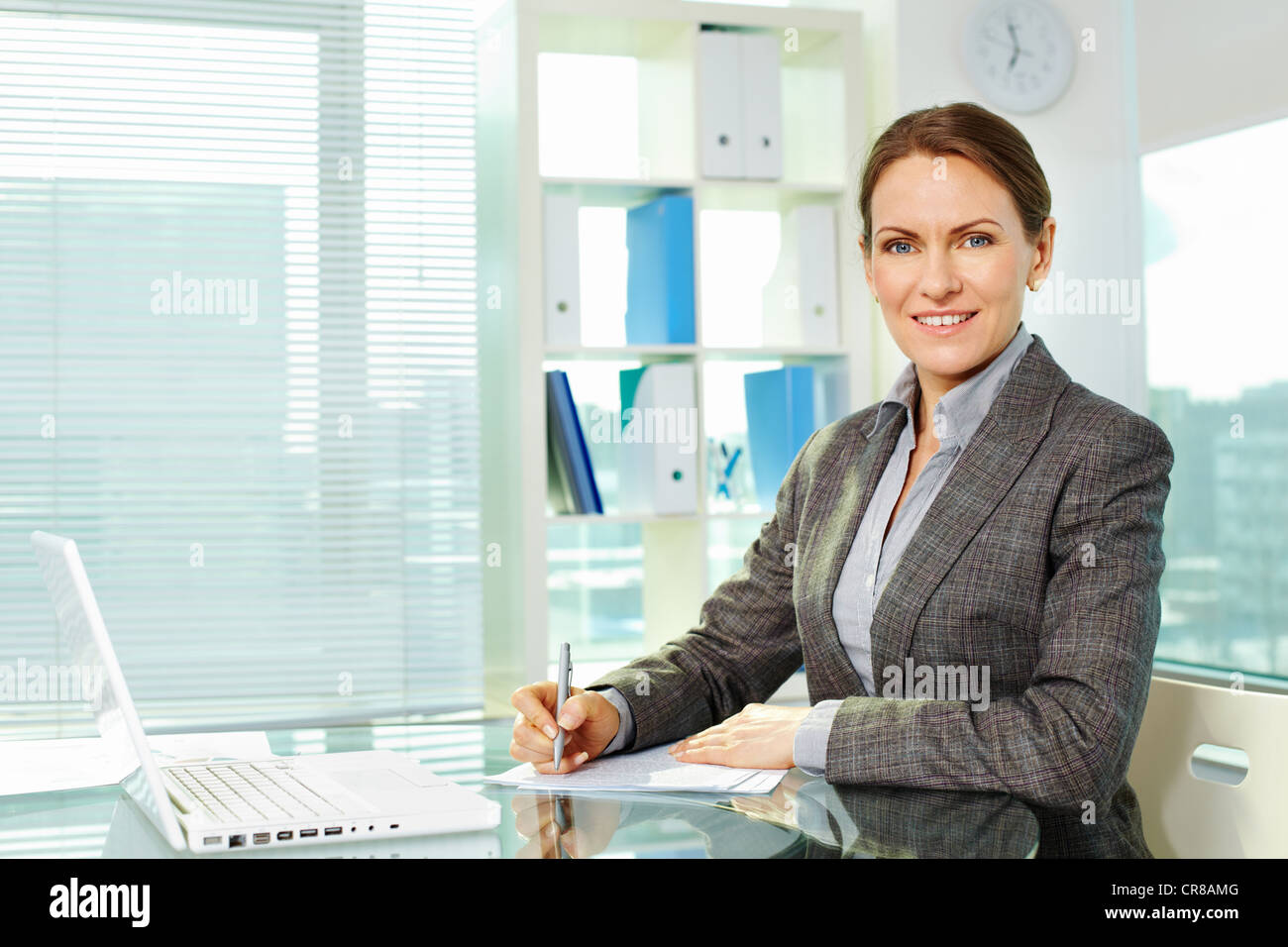 Cheerful business lady smiling at camera sitting at her workplace Stock ...