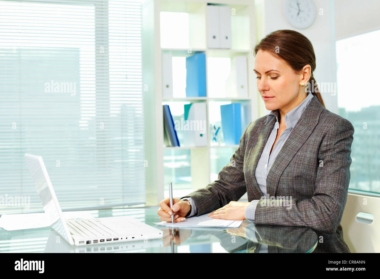Pretty business lady sitting at her workplace and making notes Stock ...