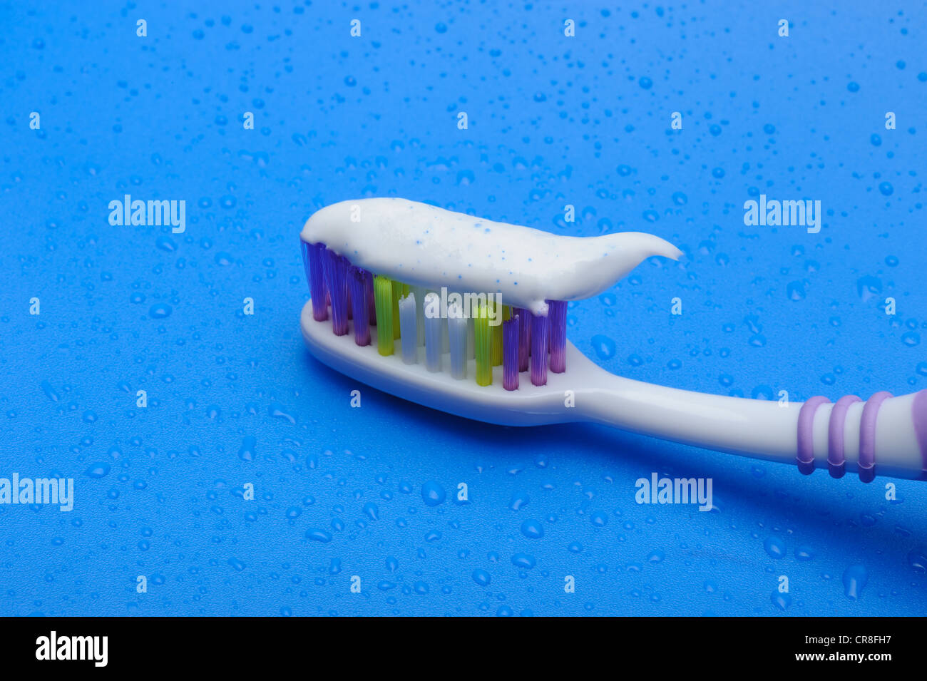 Toothbrush on a blue background with the toothpaste and drops of water ...