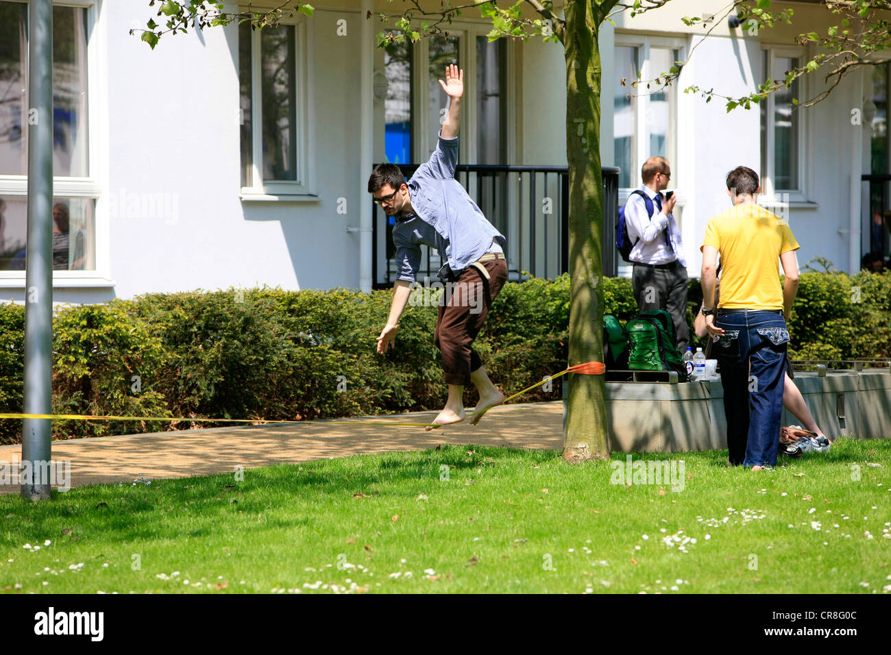 Male Student enjoy a makeshift trapeze wire during an afternoon break ...