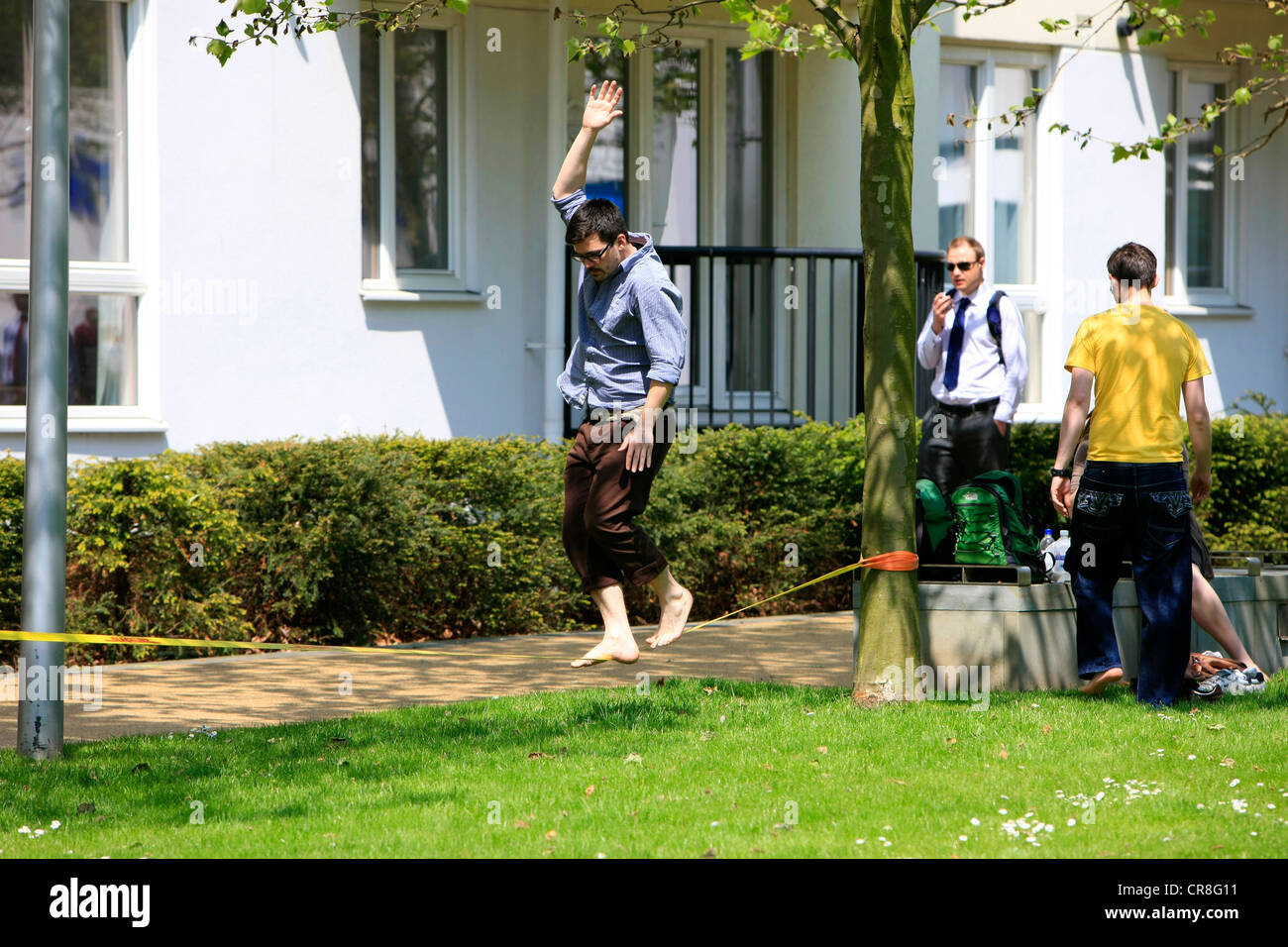 Male Student enjoy a makeshift trapeze wire during an afternoon break ...