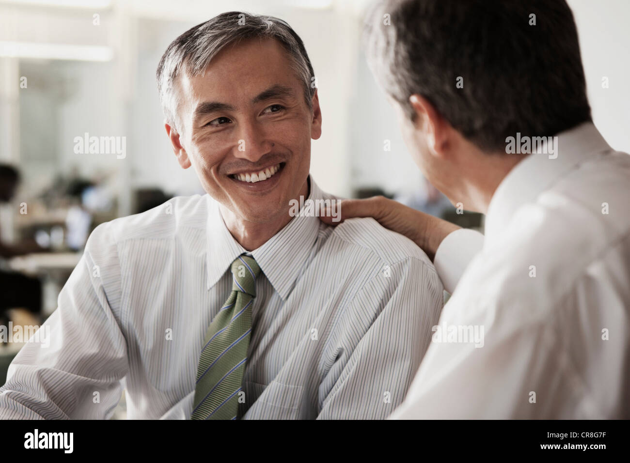 Businessman touching colleagues shoulder in office Stock Photo - Alamy