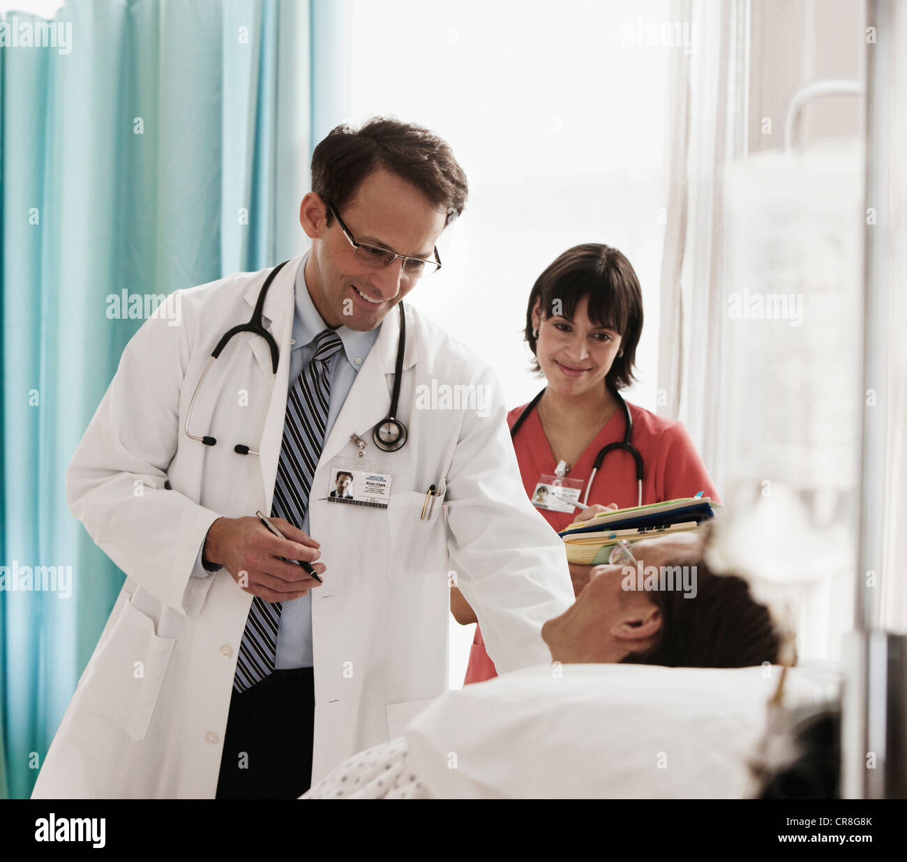 Doctor and nurse checking on patient in hospital bed Stock Photo - Alamy