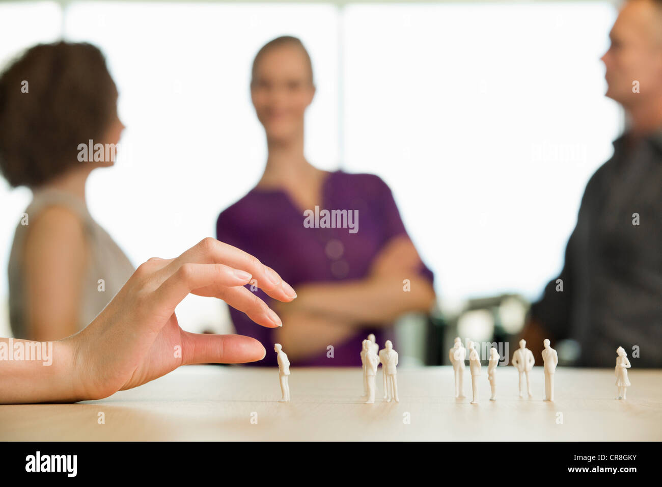Architect's hand touching model figures on desk Stock Photo - Alamy