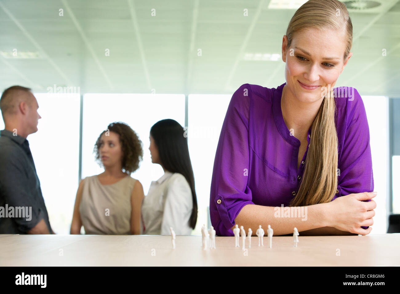 Young architect sitting at desk with model figures Stock Photo - Alamy