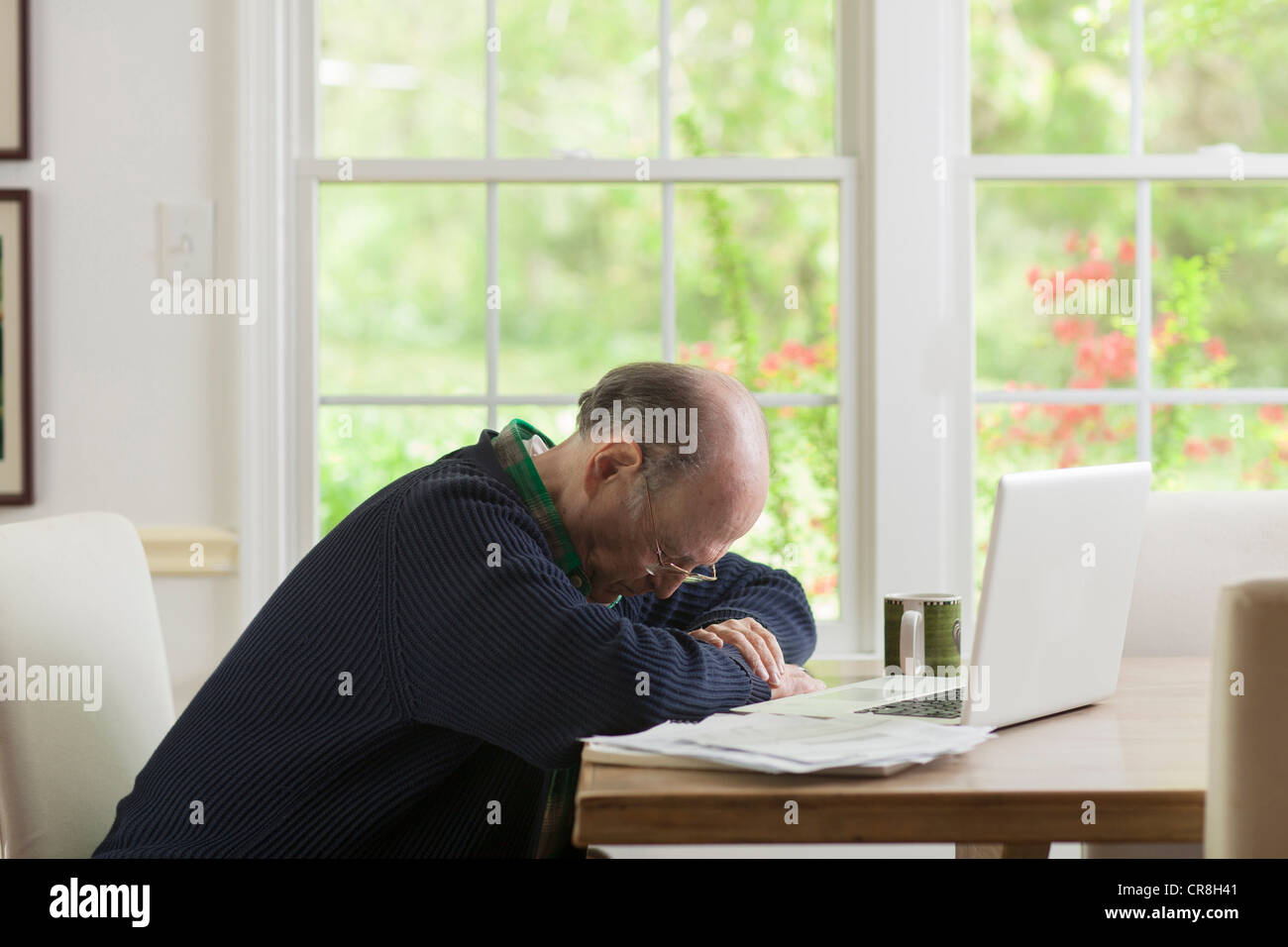 Senior man looking down at table Stock Photo - Alamy