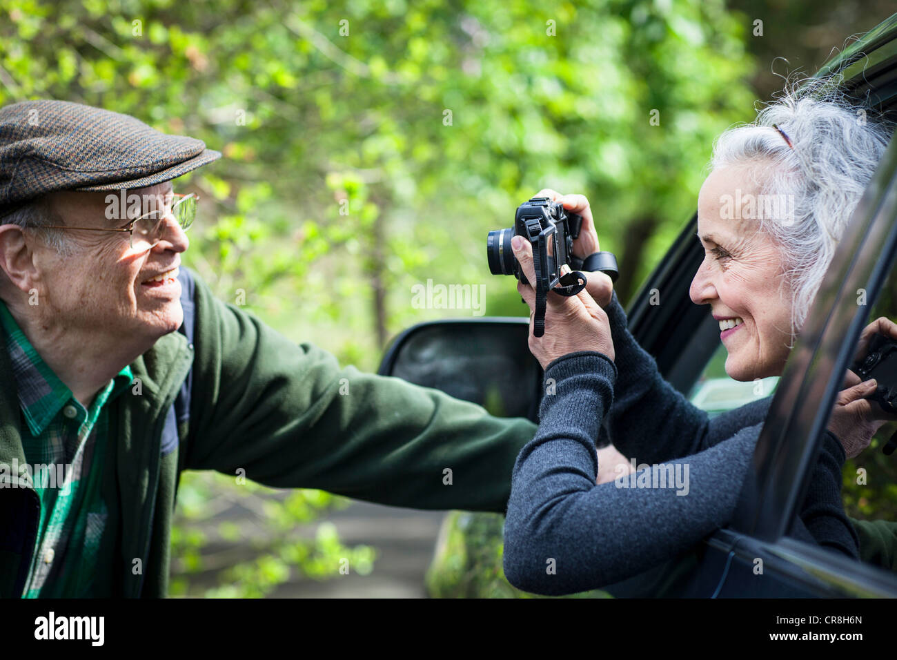 Senior woman photographing man from car Stock Photo - Alamy