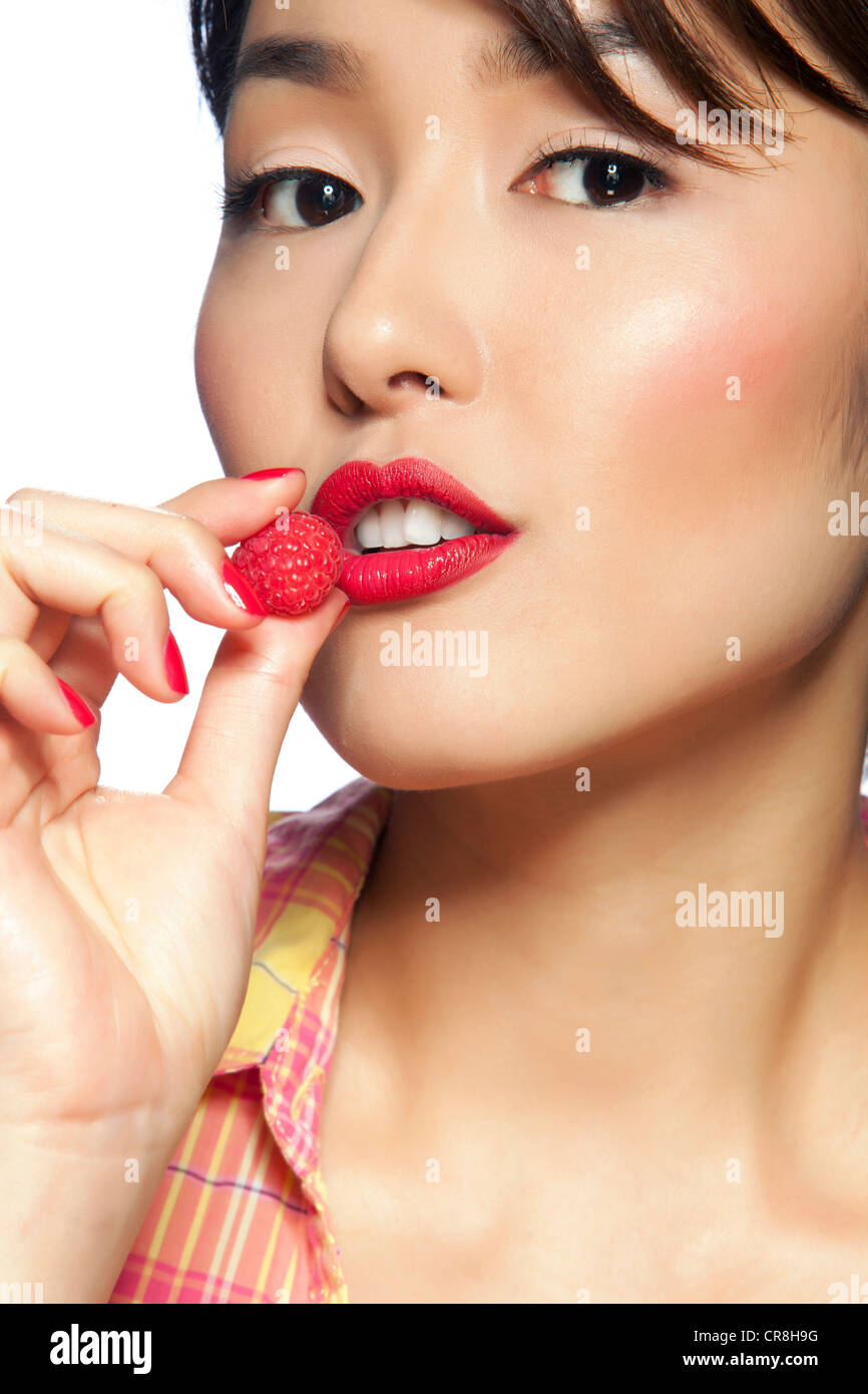 Young woman eating raspberry, portrait Stock Photo - Alamy