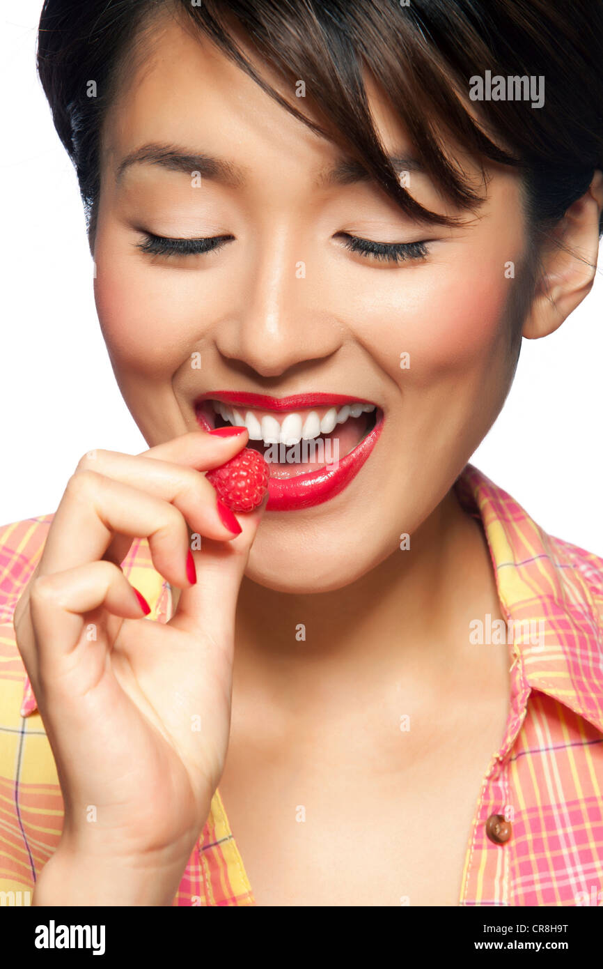 Young woman eating raspberry, studio shot Stock Photo - Alamy
